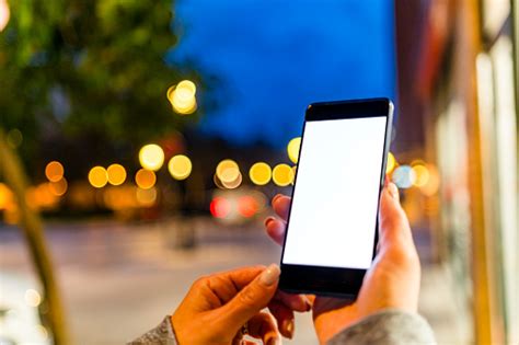 밤에 도시에서 야외에서 빈 화면 휴대 전화를 들고 있는 여자의 손을 클로즈업합니다 Brand Name Online Messaging Platform에 대한 스톡 사진 및
