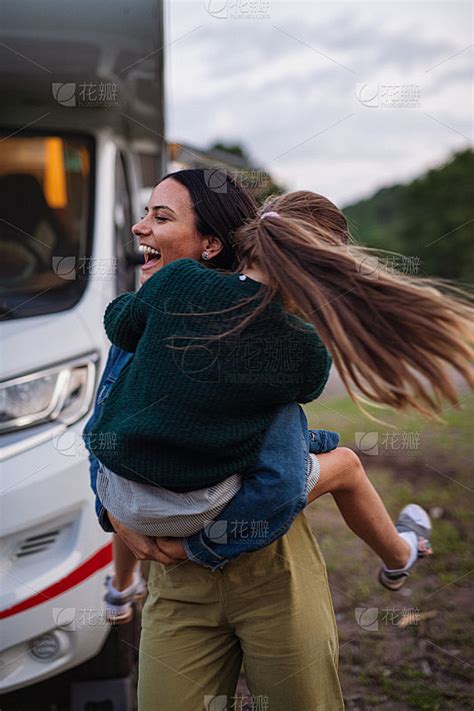 黄昏时分，妈妈带着女儿在户外露营地玩房车，一家人一起度假旅行。