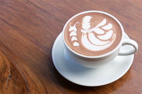 나무 테이블 복사 공간으로 커피 전문점에서 라 떼 아트 거품으로 커피 컵 커피는 가장 인기 있는 음료 중 하나입니다 에너지