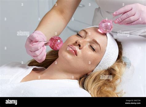 Young Woman Receiving Facial Massage With Glass Balls In Beauty Salon