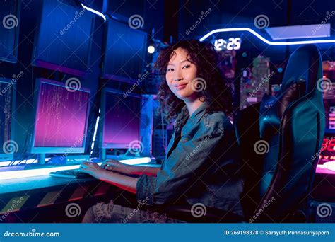 Female Asian Hacker Smiling In Hideout Place With Dark Environment And Multiple Displays And