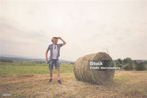 잔디밭에서 둥근 건초 베일 옆에 서있는 카우보이 모자를 쓰고 있는 성인 농부 건조한에 대한 스톡 사진 및 기타 이미지 건조한 건초 식물 건초 재배 식물 Istock