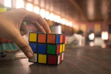 Premium Photo Hand Holding A Rubiks Cube On A Wooden Table
