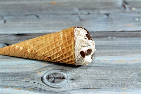 바삭한 웨이퍼 콘에 초콜릿 칩 조각을 토핑한 아이스크림 바닐라 콘 웨이퍼 비스킷에 차가운 아이스크림 돌리기를 녹이는 선택적 초점 거품 내기에 대한 스톡 사진 및 기타 이미지