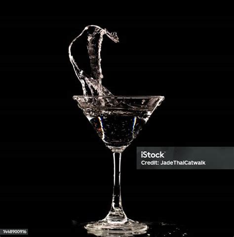 물 알코올이 튀는 칵테일 잔 크리스탈 칵테일 음료가 공기 중에 튀고 유리에서 거품이 튀어 나옵니다 주류 부품 동결 샷 격리된 검은색 배경 위에 고속 마티니에 대한 스톡 사진