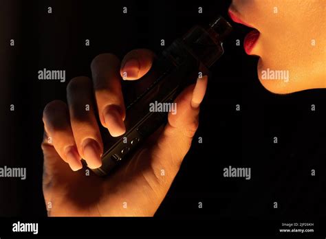 A Girl Smokes An Electronic Cigarette And Exhales Smoke Her Lips Are
