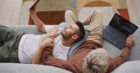 Top View At Contemporary Gay Couple Using Computers While Relaxing On