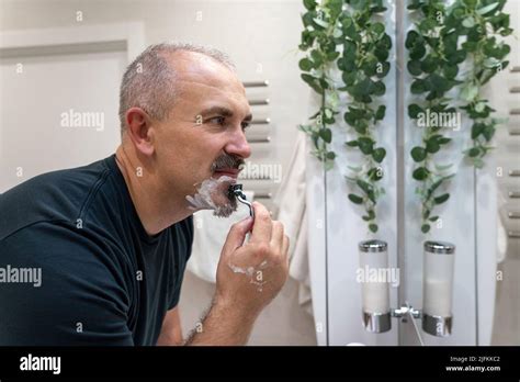 Man Shaving With Razor Using Foam In Bathroom In The Morning Stock