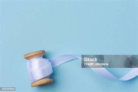 옅은 파란색 배경에 나무 스풀에 압 연 곱슬 흰색 실크 리본 소용돌이 바느질 결혼식 약혼 패션 공예 취미 개념입니다 깨끗 한