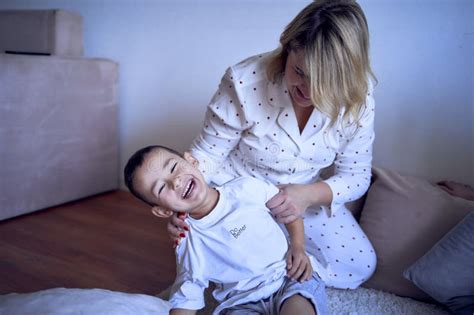 A Mother Plays And Drags Her Little Son On A Sheet Around The Room