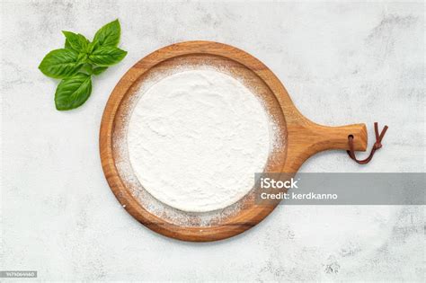 흰색 콘크리트 위에 설치된 나무 피자 플래터에 피자 반죽 흰색 콘크리트 배경에 피자 트레이가 평평한 누워 있고 복사 공간