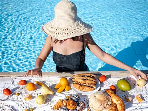 Girl In The Pool In A Straw Hat With Assorted Breakfast Meal And Drinks