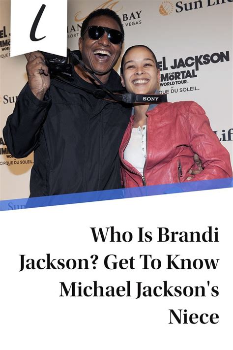 A Man And Woman Standing Next To Each Other In Front Of A Sign That