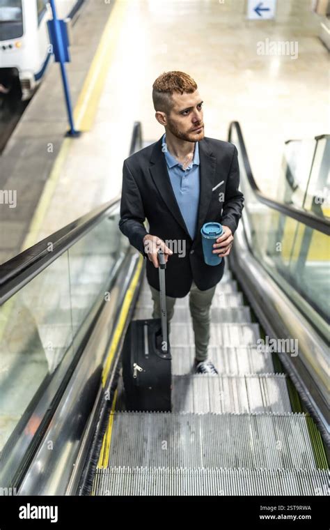 Businessman Going Up Escalator In Subway Station Holding Reusable