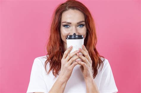Female With Ginger Hair Using Disposable Cup Of Take Away Coffee