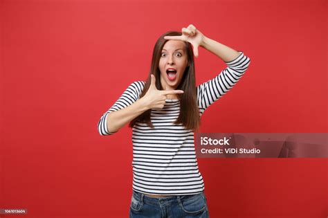 흥분된 젊은 여성 입 벌리고 유지 찾고 손 사진 프레임 제스처 밝은 빨간 벽 배경에 고립 된 만들기 사람들이 진심으 감정 라이프 스타일 개념 복사 공간을 비웃는 다 갈색