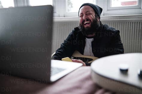 Mature Man With Laptop Laughing At Home Stock Photo