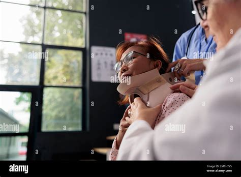 Medical Assistant And Doctor Helping Senior Patient With Cervical Neck