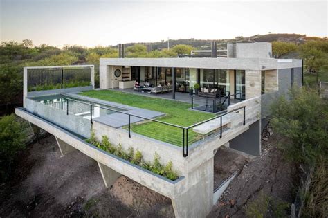 Консольный бетонный дом с минималистичным фасадом и зеленой кровлей