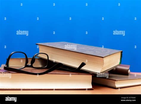 Books And Eyeglasses On A Wooden Table On Blue Trendy Soft Background