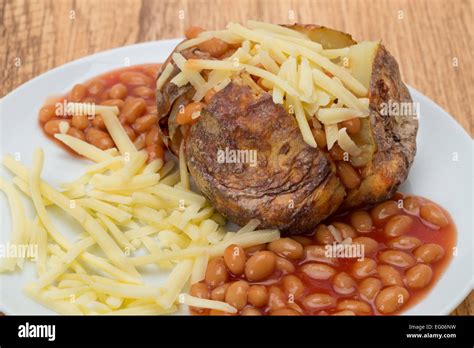 A Hot Baked Jacket Potato Full Of Grated Cheese And Baked Beans