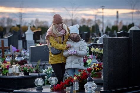 Mother And Daughter Remembrance In A Quiet Cemetery At Dusk Surrounded