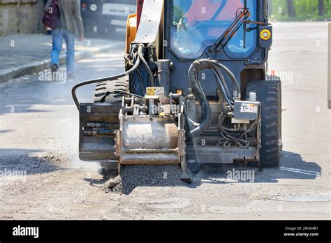 A Road Construction Tractor With A Mounted Milling Machine Is Repairing