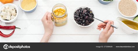 cropped view woman adding beans jar salad wooden white table — stock
