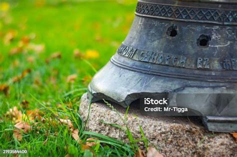 야외의 콘크리트 바닥에 설치된 풍화 된 금속 종 비문과 어두운 녹청 잔디와 낙엽으로 둘러싸인 배경에는 녹색 단풍이 나타납니다 개념에 대한 스톡 사진 및 기타 이미지 Istock