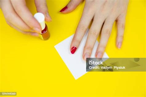 여자는 노란색 배경에 빨간색 매니큐어를 적용합니다 N소녀 만들기 매니큐어 집에서 살롱 절차 아름다운 손과 손톱 클로즈업 매크로 사진 화려하고 창조적인 개념에 대한 스톡 사진
