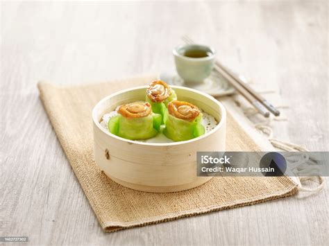 Abalone과 함께 찐 새우 만두는 회색 대리석 배경의 매트 측면보기에 격리 된 젓가락이있는 나무 그릇에 담겨 제공됩니다