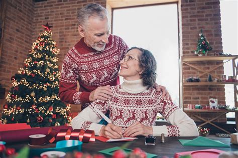 긍정적 인 평화로운 은퇴 한 부부의 사진은 Xmas 워크샵 쓰기 편지 착용 장식 풀오버 홈 실내를 준비합니다 2명에 대한 스톡
