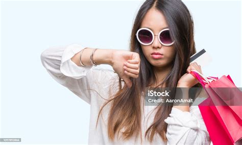 젊은 아시아 여자와 성 난 얼굴 아래로 엄지 싫어 보여주는 음수 부호 거부 개념 고립 된 배경 위에 판매 쇼핑 가방을 들고 가방에 대한 스톡 사진 및 기타 이미지 Istock