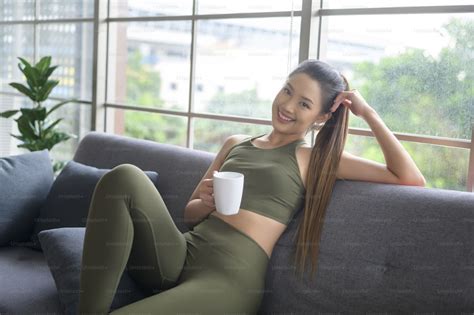 운동복을 입은 젊은 피트니스 여성이 집에서 운동한 후 커피 한 잔을 마시고 있다 사진 Unsplash의 한 사람 이미지