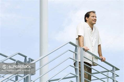 Man Leaning Against Railing Looking Into Distance Low Angle View SuperStock