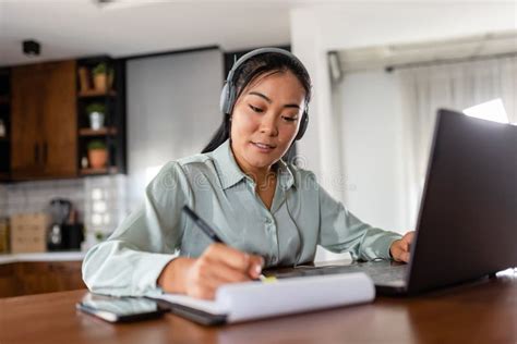 Young Asian Woman Working From Home Sitting In Front Of Laptop