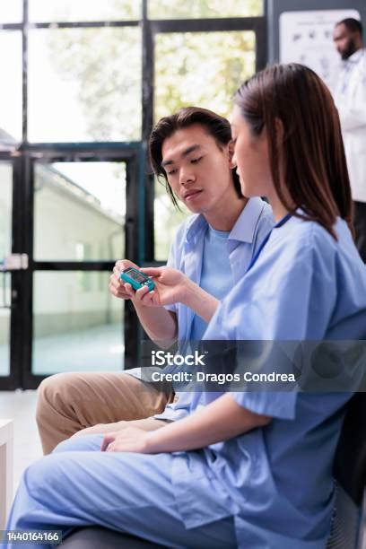 인슐린과 포도당 수치를 측정하는 동안 글루코 미터로 아시아 환자와 상담하는 의료 보조 간호사에 대한 스톡 사진 및 기타 이미지