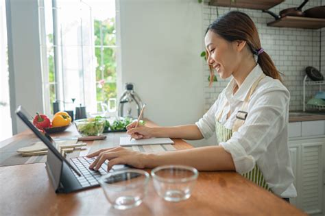 노트북 컴퓨터를 사용하여 부엌에서 신선한 야채와 과일로 건강에 좋은 음식을 요리하는 것을 배우는 젊은 아름다운 여성 가정 생활에 대한 스톡 사진 및 기타 이미지 Istock