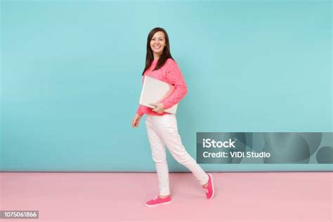 화이트 니트 장미 스웨터 바지 노트북 Pc 컴퓨터를 들고 있는 여자의 전체 길이 초상화 스튜디오에서 밝은 핑크 블루 파스텔 벽