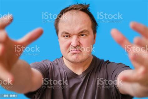 흐트러진 모습의 성인 남자의 초상화는 팔을 앞으로 당기고 푸른 스튜디오 배경을 가지고 있습니다 40 44세에 대한 스톡 사진 및