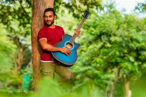 Premium Photo Portrait Of A Babe Clinging To A Tree Is Playing The Guitar