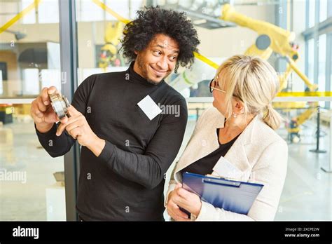 Two Engineers Engaging In A Lively Discussion About Robotic Automation And Gripper Arms In An