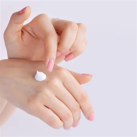 Premium Photo Young Woman With Pink Manicure Applies Cream On Her Hands