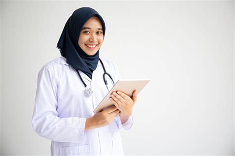 젊은 아랍 무슬림 인턴 의사 여성은 의료 병원 건강 관리에서 일하는 이슬람 사람들을위한 백색 배경 개념을 고립시키는 미소 현대