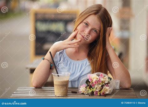 Милая девушка сидя на кафе улицы и выпивая Smoothies на городской