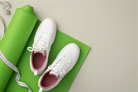 피트니스 개념 고립 된 파스텔 회색 배경에 녹색 스포츠 매트 위에 테이프와 흰색 운동화를 측정하는 상단보기 사진 개념에 대한