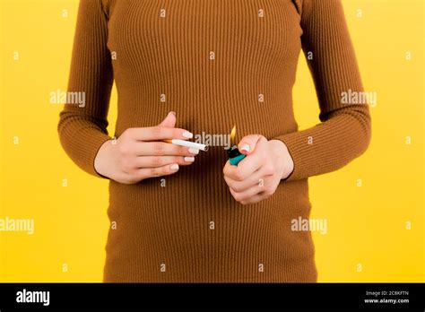 Close Up Of A Cigarette And A Lighter In Pregnant Womans Hands At