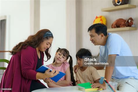 행복한 아시아 가정은 의자에 앉아 집에서 거실에서 함께 책을 읽고 가족 시간을 보낼 때 교육을 받았습니다 4 명에 대한 스톡