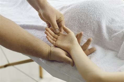 Male Masseur Doing Relaxing Hand Massage To Young Woman Lying On