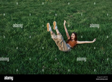 A Young Woman Playing Games In The Park On The Green Grass Spreading